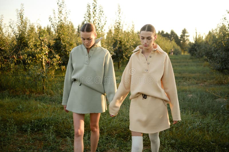 Two Models in Stylish Tracksuits Pose in Apple Orchard at Sunset . the ...
