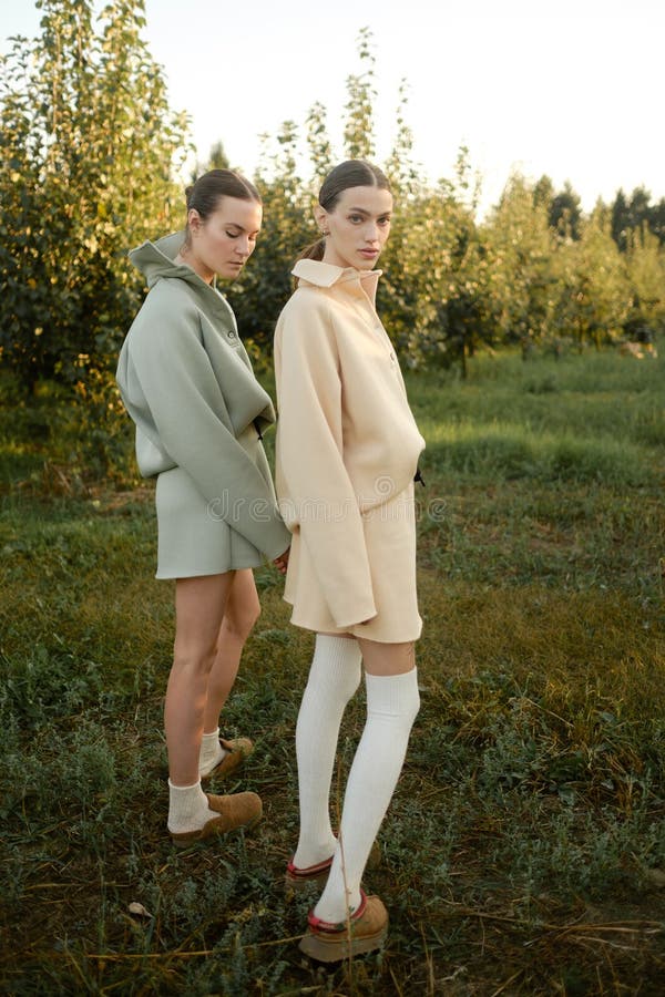 Two Models in Stylish Tracksuits Pose in Apple Orchard at Sunset . the ...