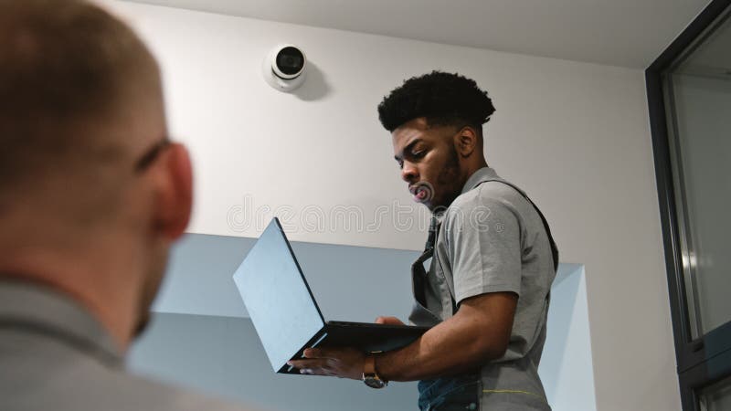 Two Multi Ethnic Installers Sets Up Security Cameras in Office Hallway Stock Photo - Image of ...