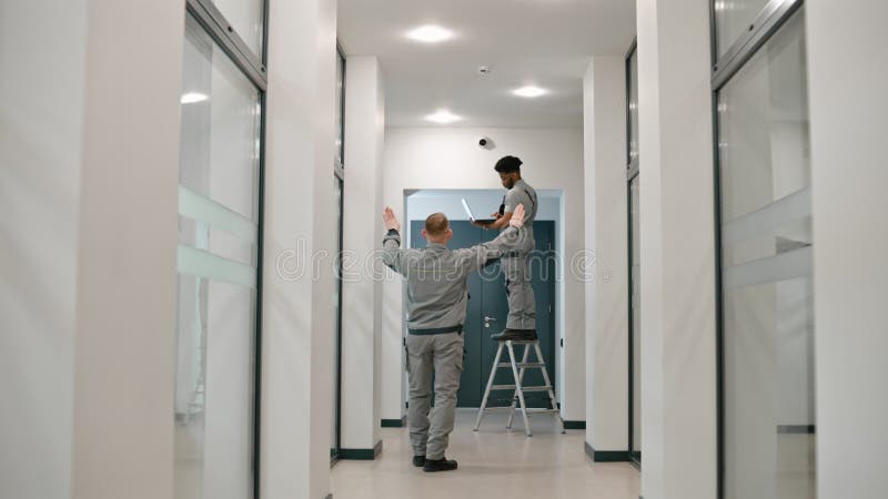 Two Multi Ethnic Installers in Uniform Sets Up Security Camera Stock ...