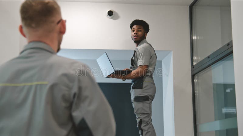 Multi Ethnic Installers Sets Up Security Camera in Office Hallway Using ...