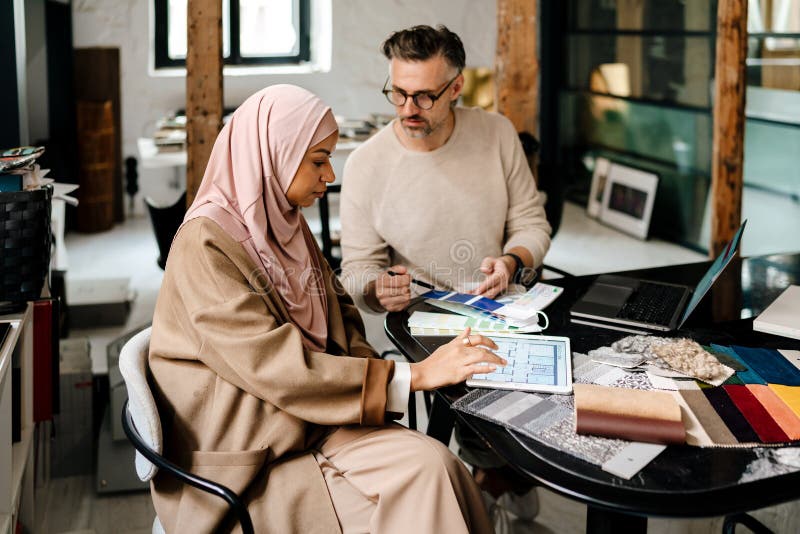 Two Multinational Colleagues Working on Computers Together at Workshop ...