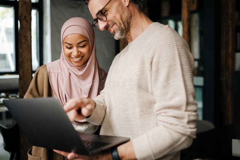Two Multinational Colleagues Working with Laptop Computer in Office ...