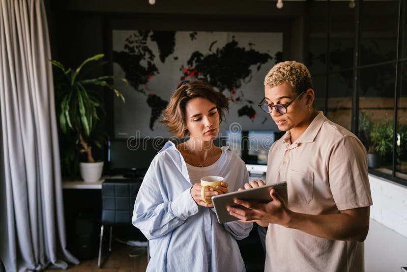 Two Multinational Colleagues Using Tablet while Standing in Office ...