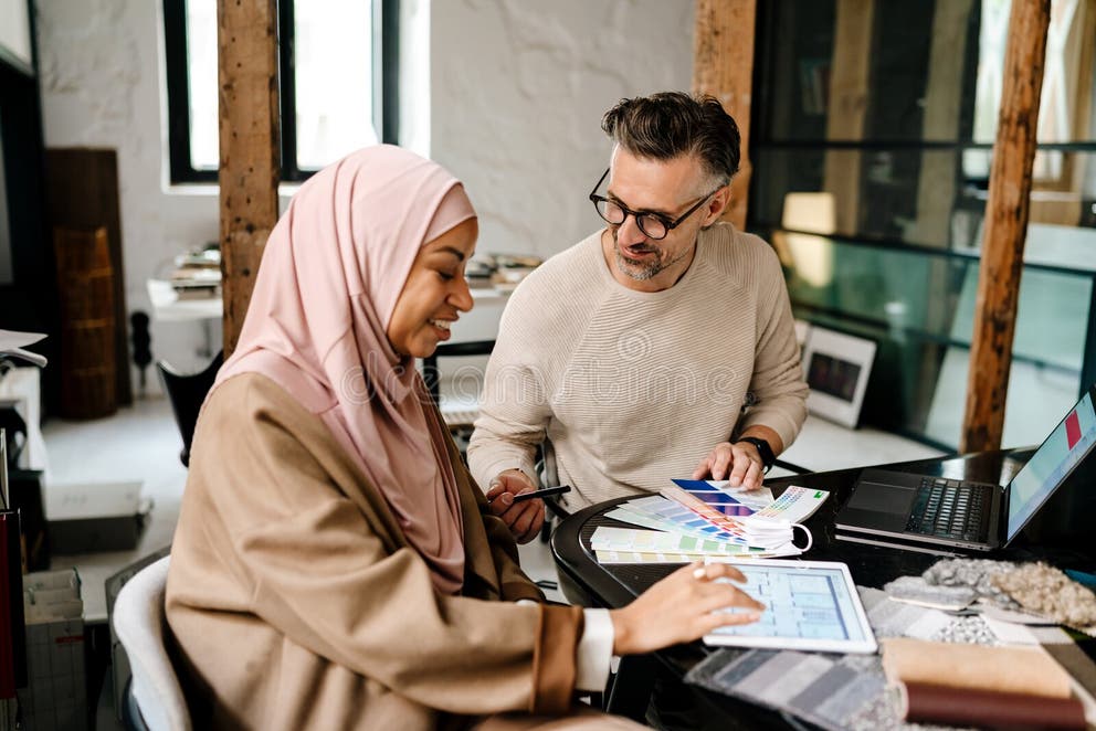 Two Multinational Colleagues Working on Computers Together at Cozy ...