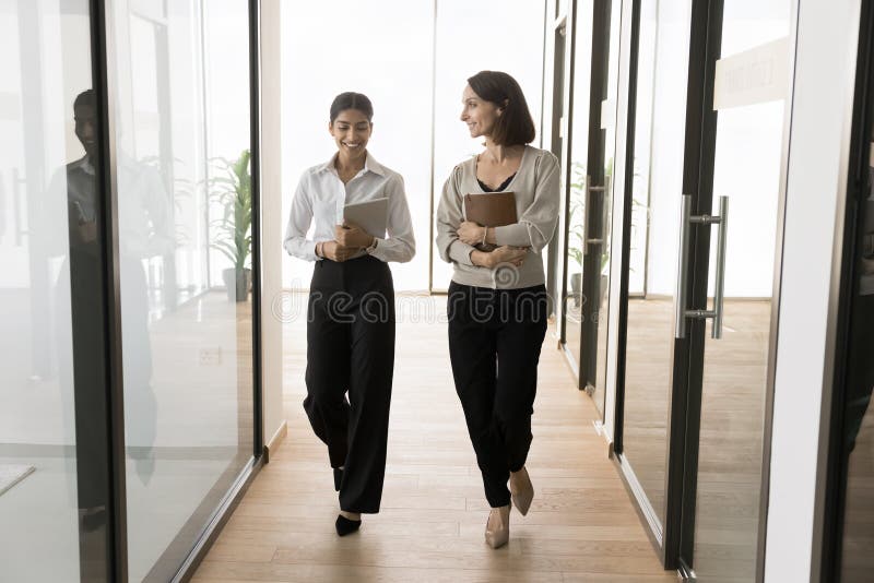 Two Multiracial Colleagues Walking and Talking in Modern Office ...
