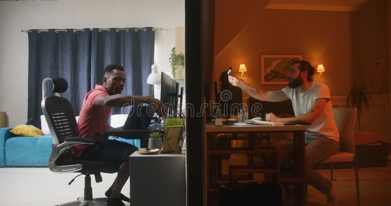 Two Multiracial Men Sit in Front of Computers in Bedrooms Stock Photo ...