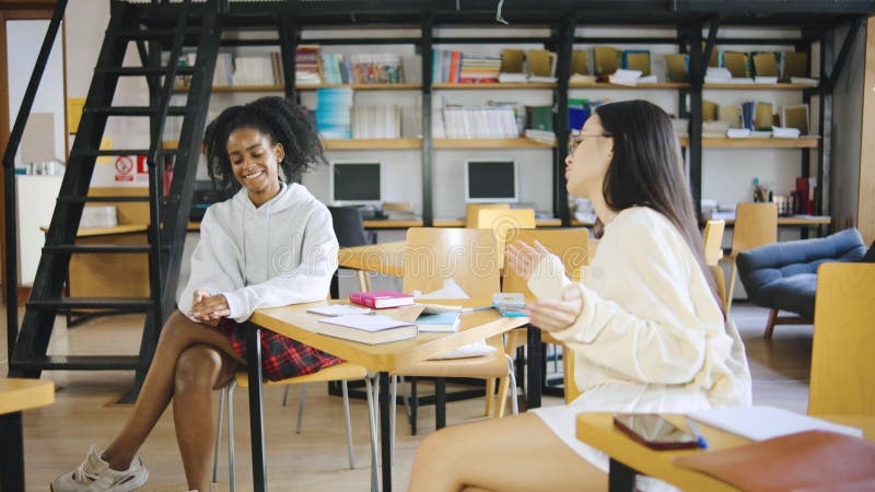 Two Multiracial Students Engaged in a Lively Discussion while Studying ...