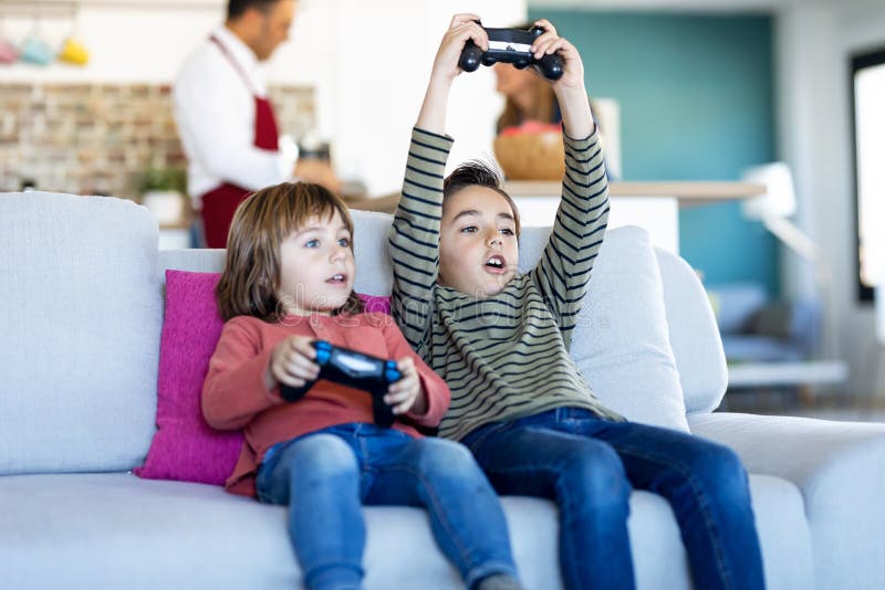 Two Nice Brothers Playing Video Games while Sitting on the Sofa at Home ...