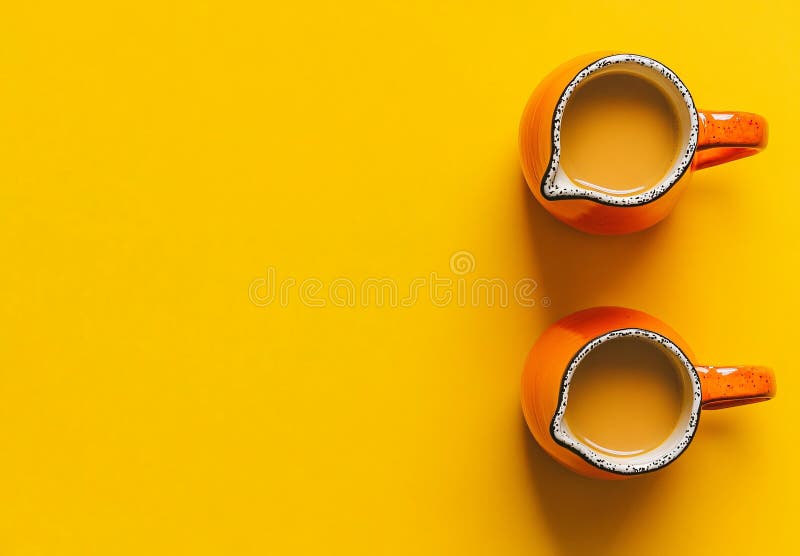 Two Orange Creamer Pitchers on Yellow Background High Quality Image ...