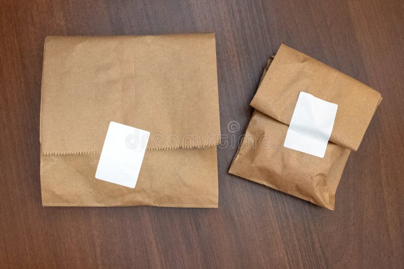 Two Packed Paper Bags Sealed with a White Sticker are on the Table. the ...