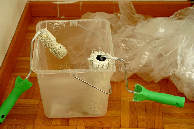 Two Paint Rollers in a Container on the Floor. the Paint is Dripping ...