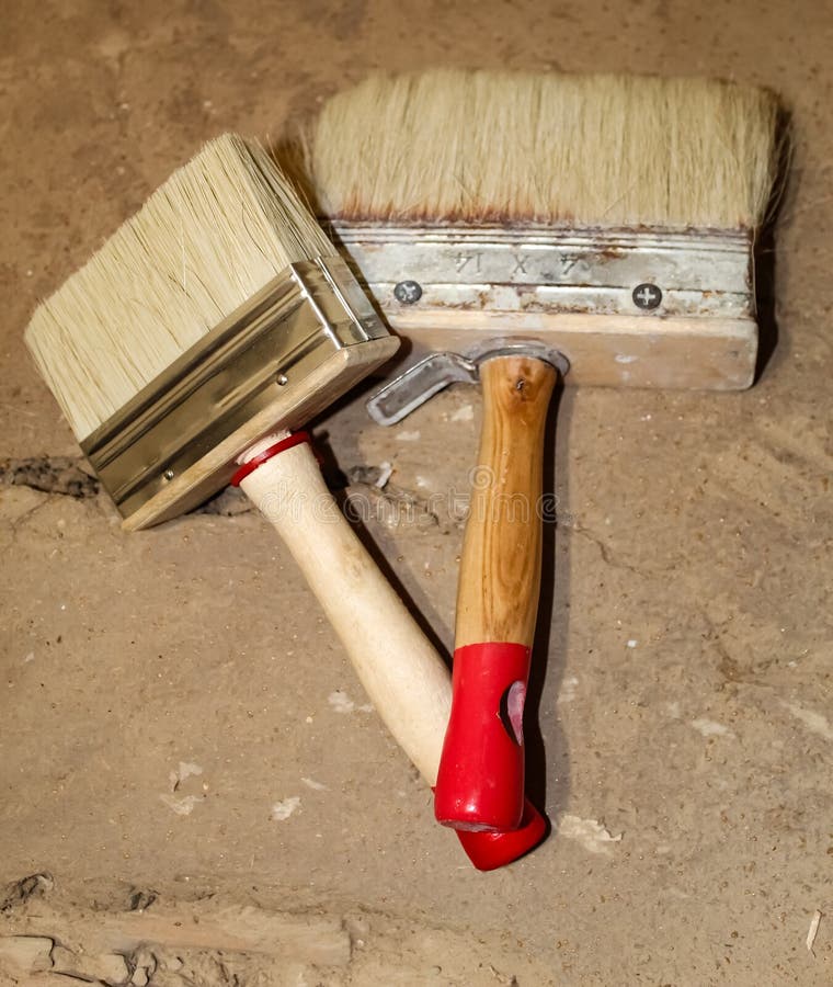 Two Paintbrushes with Wooden and Metal Handles Resting on a Textured ...