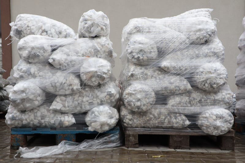 Two Pallets with Bags Containing Bags with a White Round Stone Stock ...
