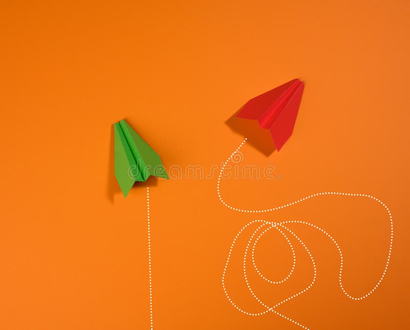 Two Paper Airplanes with Different Trajectory of Movement on an Orange ...