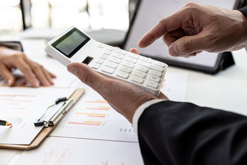 Two People Checking Numbers on Documents Using Calculators, Business ...