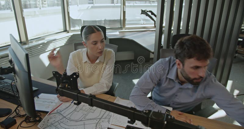 Two People Collaborate on Blueprints in a Modern Office, Discussing ...