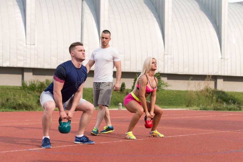 Two People Doing Kettlebell Exercise Outdoor with Instructor Stock ...