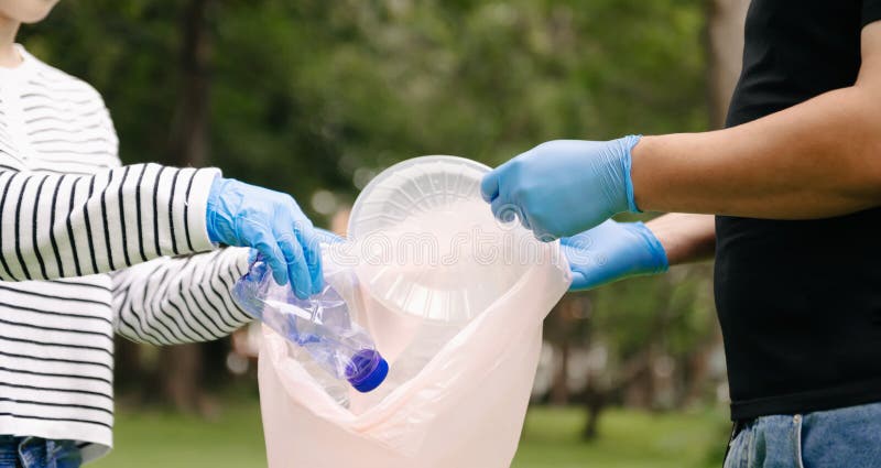 Two People Keeping Garbage Plastic Bottle into Black Bag at Park ...