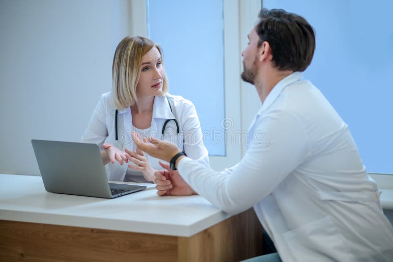 Two People in Lab Coats Discussing Something and Looking Interested ...