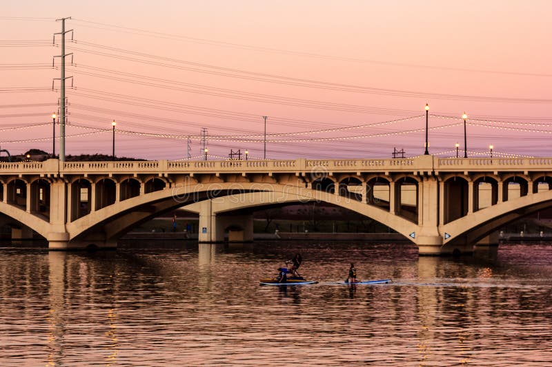 Two People are on a Paddle Board in the Water Under a Bridge Stock ...