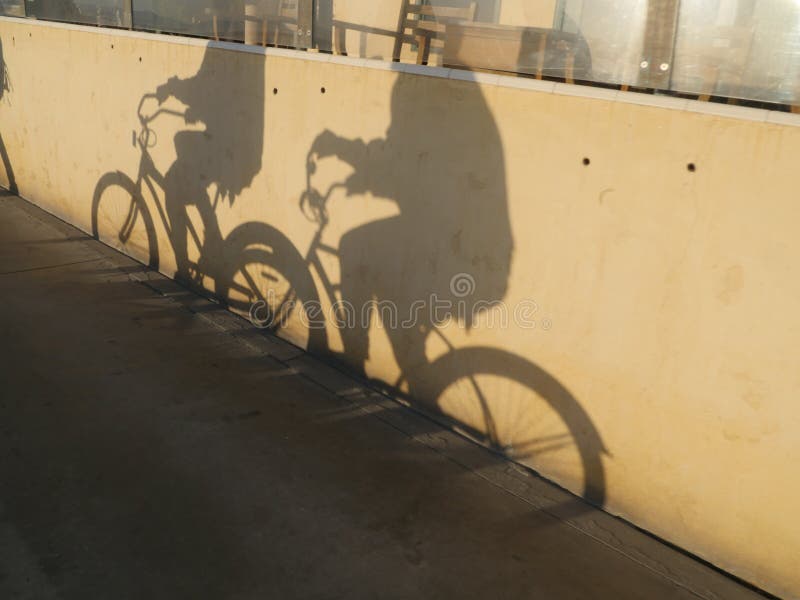 Two People Riding Bikes. Their Shadows on Wall. Stock Image - Image of ...