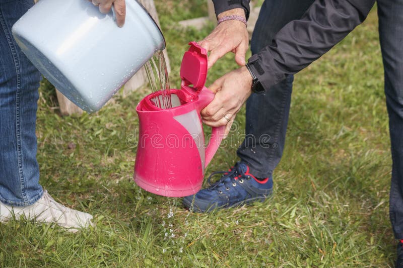 .two People are Seen Pouring Liquid from One Container To Another Stock ...
