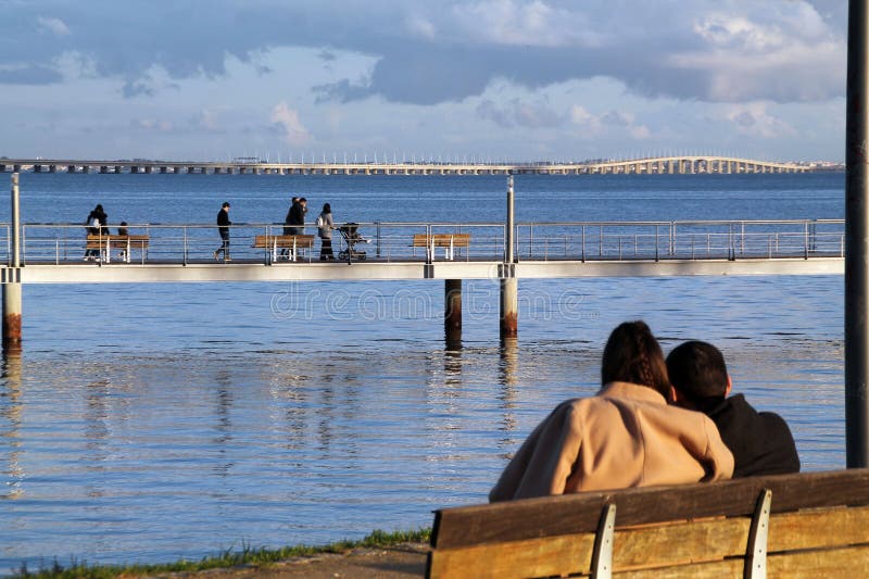 Two People Sitting Side by Side on a Wooden Bench Overlooking the Beach ...
