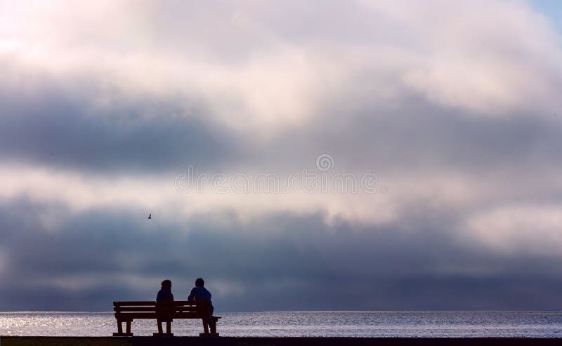 Two People Sitting on a Street Bench and Watching the Dramatic Sunset ...