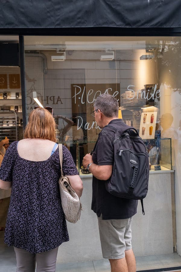 Two People Stand in Front of a Shop Window, Both Looking Inside the ...