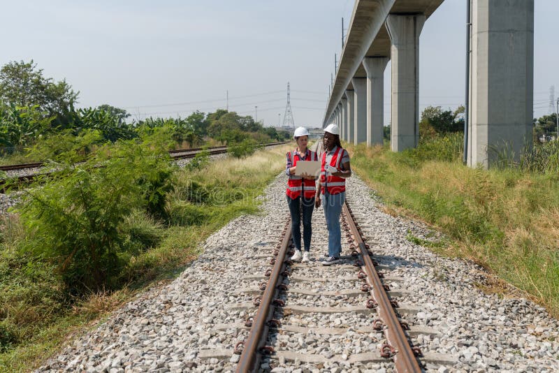 Two People are Standing on Railroad Tracks and Looking at Laptop ...