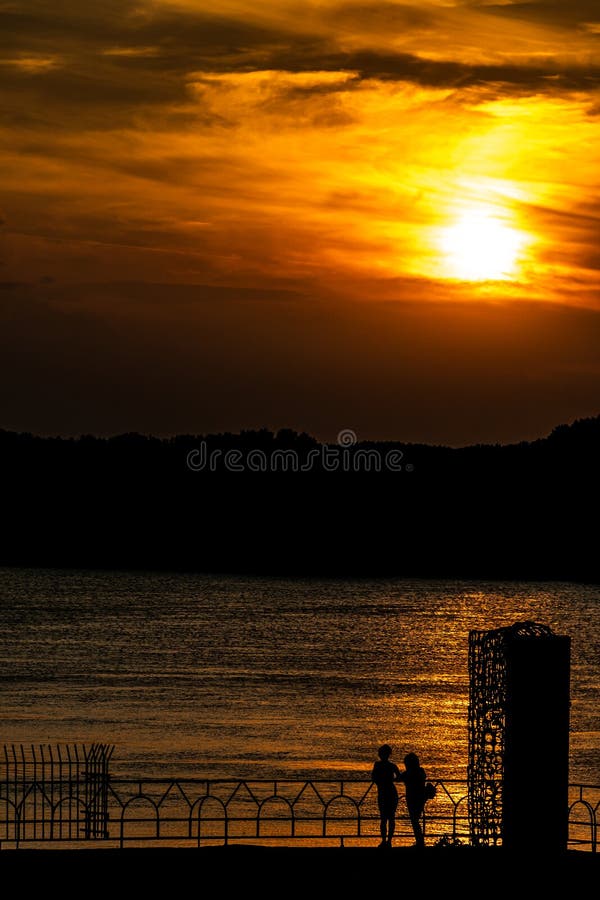 Two people at sunset stock photo. Image of reflection - 247816576