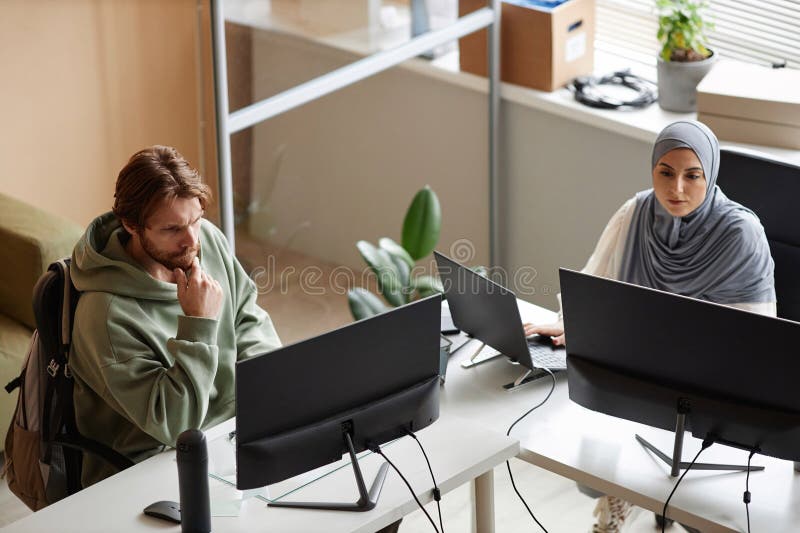 Two People Using Computers at Desk in Office with Wall Separations ...