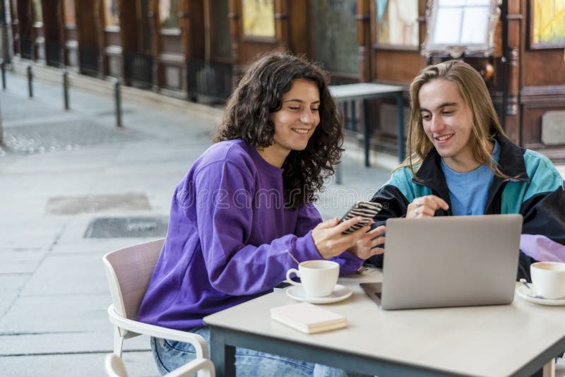 Two People Using Laptop and Mobile Phone while Sitting Outdoors at a ...