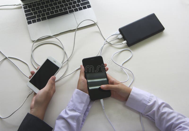 Two People Using Two Mobile Phone Sharing USB Power Bank on a Table To ...