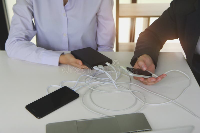 Two People Using Two Mobile Phone Sharing USB Power Bank on a Table To ...