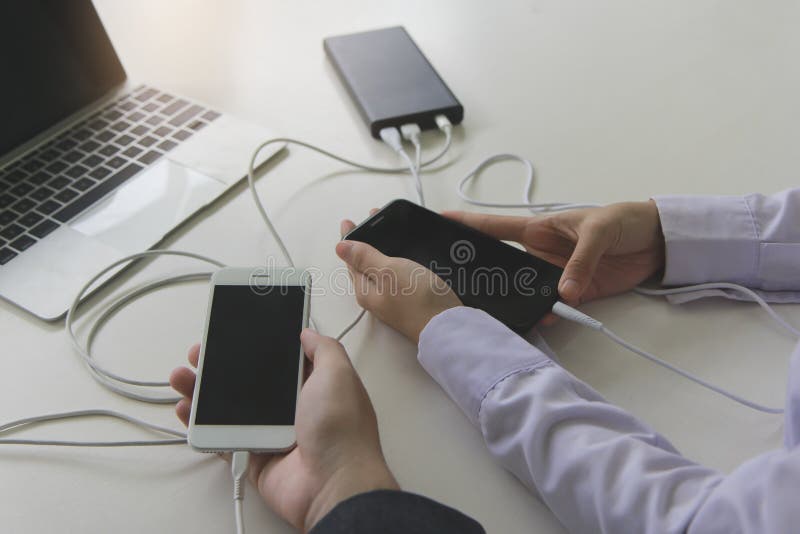 Two People Using Two Mobile Phone Sharing USB Power Bank on a Table To ...