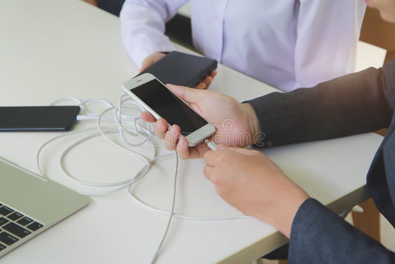 Two People Using Two Mobile Phone Sharing USB Power Bank on a Table To ...