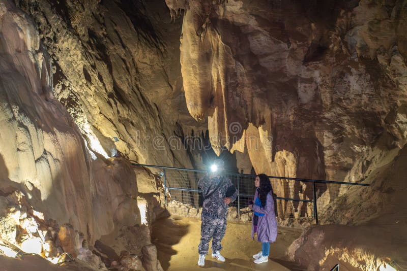 Two People are Walking through a Cave with a Light on. the Cave is Dark ...