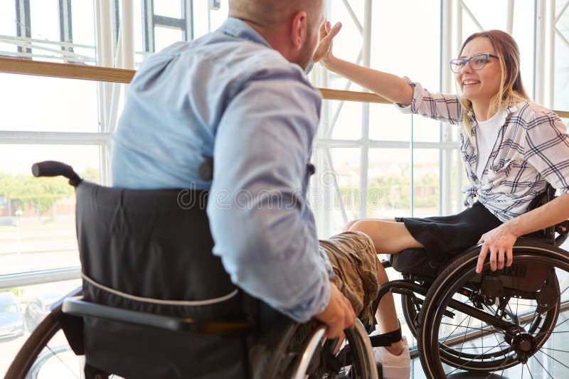 Two People in Wheelchairs Bonding Over a High-five in a Modern Office ...