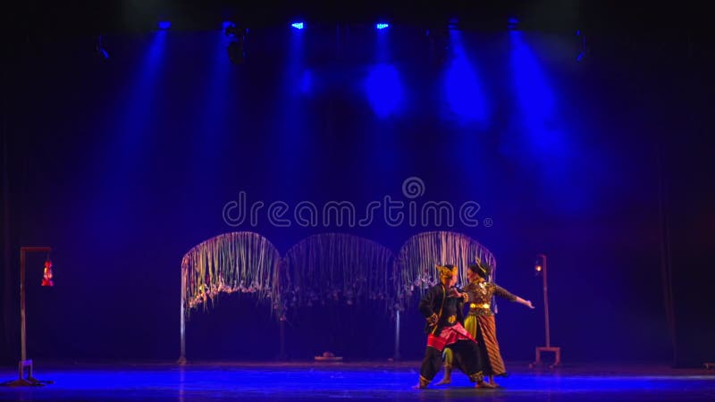 Two Performers on Stage Under Blue and Yellow Stage Lights with a Dark ...