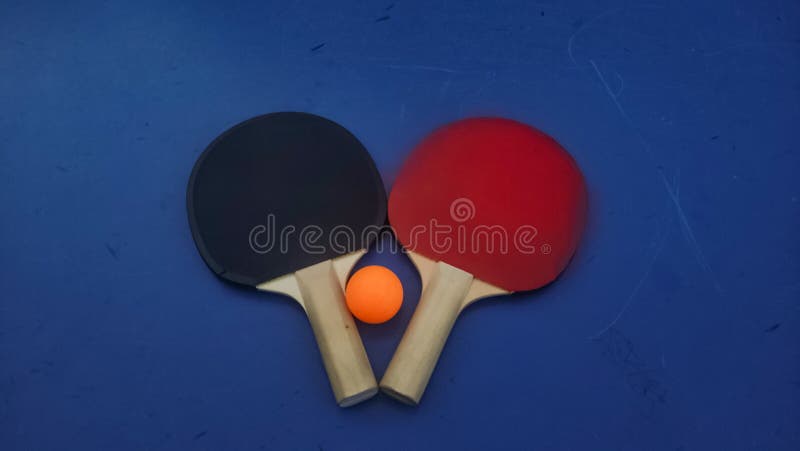 Two Ping Pong Paddles, One Black and One Red, Lay on a Blue Table with ...