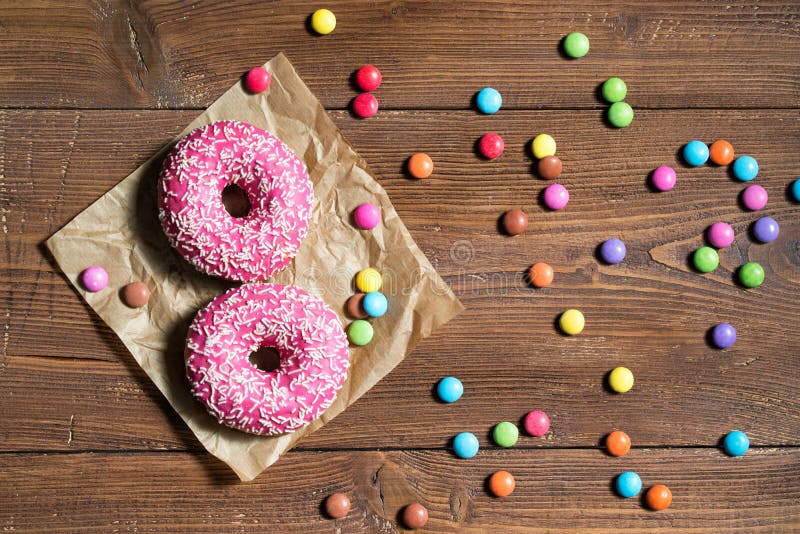 Two Pink Donuts and Colored Smarties on Wooden Table, Top View Stock ...