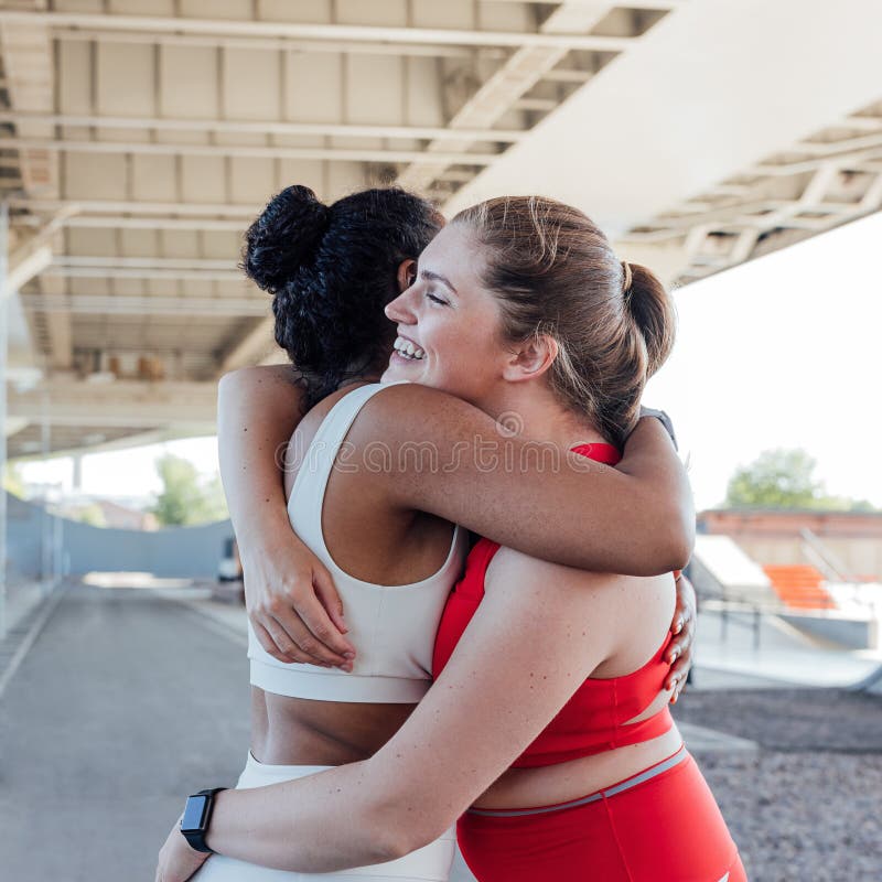 Smiling Female In Red Sportswear Embracing With Her Friend During