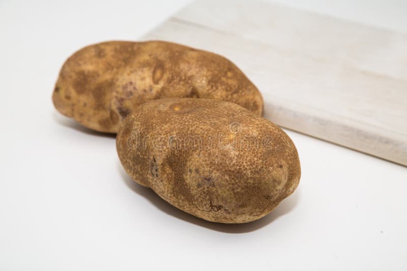 Two Potatoes on White Counter with Wood Board Stock Image - Image of ...