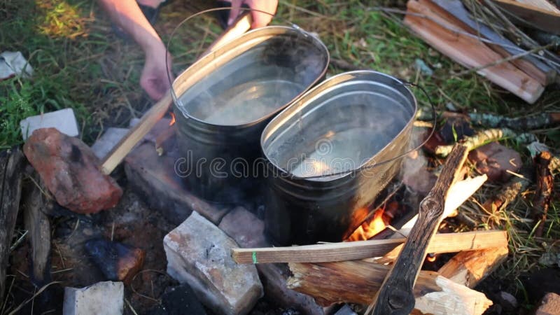 Two Pots with Water on Bricks on Campfire and Hand Stock Video - Video ...