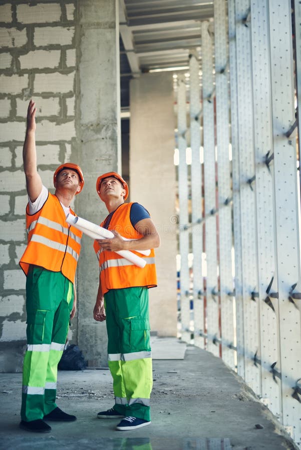 Young Builder Putting One Hand Up while Standing with Colleague Stock ...
