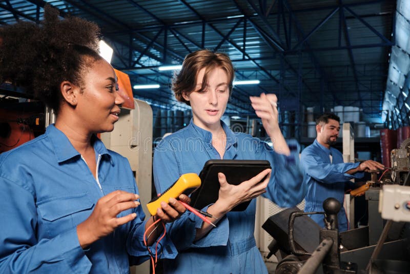 Two Professional Female Engineers Inspect Machines` Electric Systems at ...
