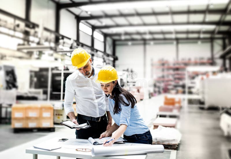 Two Project Managers Standing in Modern Industrial Factory, Looking ...