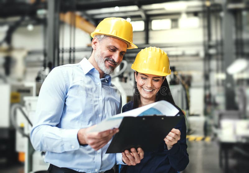Two Project Managers Standing in Modern Industrial Factory, Looking ...